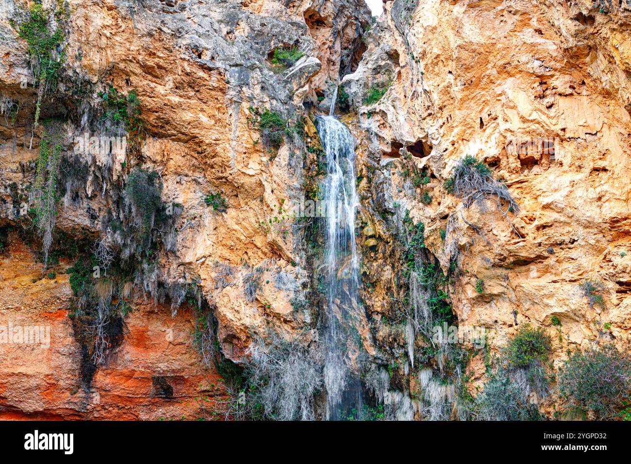 A stunning waterfall flows down from rugged cliffs, surrounded by ...