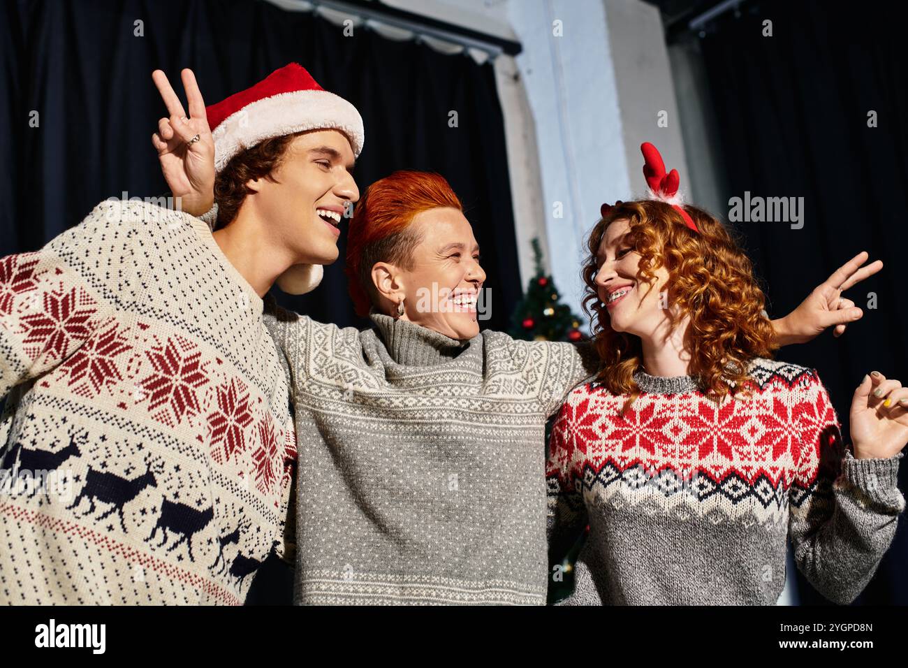 Three coworkers wear festive sweaters, sharing joy and laughter during ...