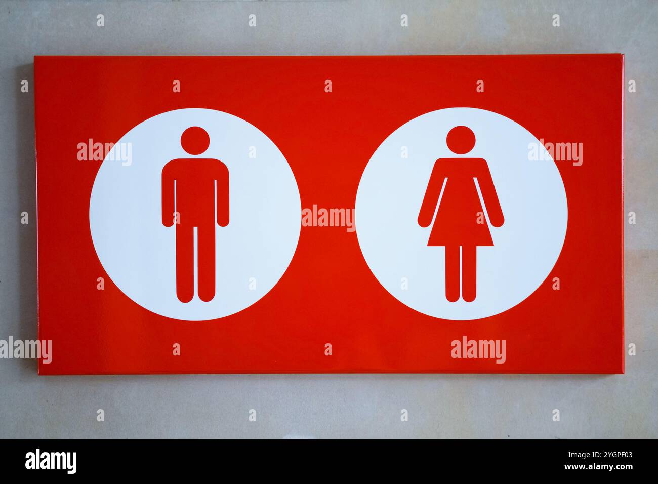 A sign displays male and female restroom symbols against a red ...