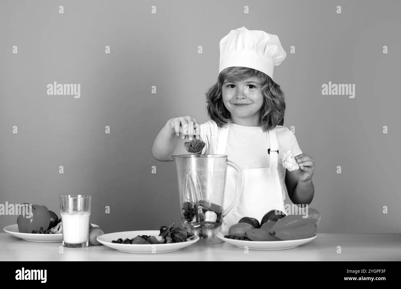 Child wearing cooker uniform and chef hat preparing vegetables on ...