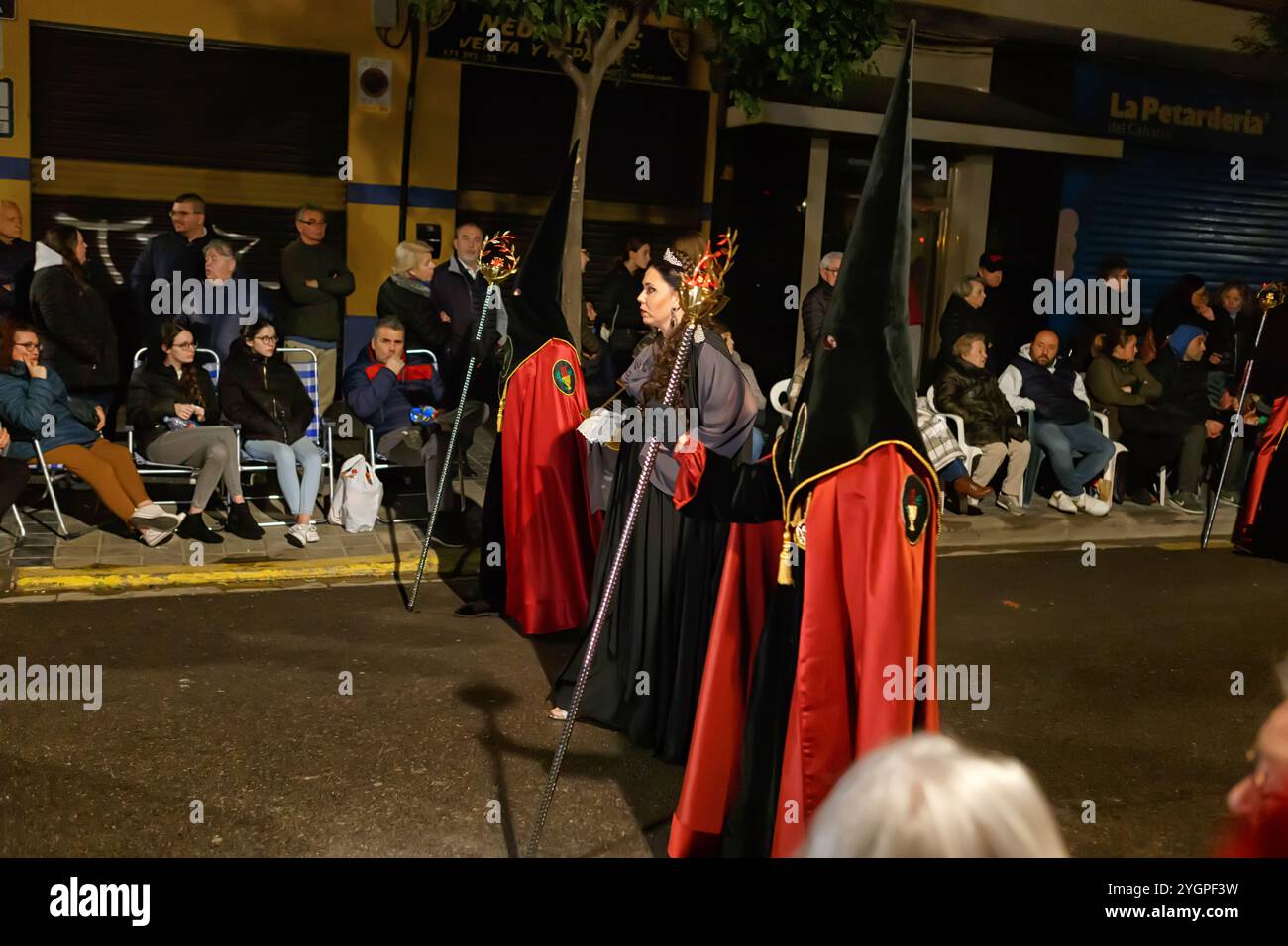 In the evening, participants in traditional attire parade down a busy ...