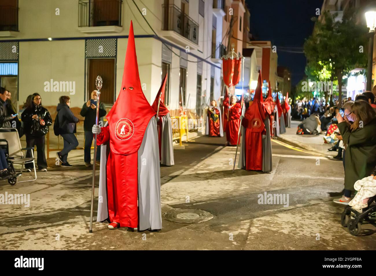 In the evening, participants in traditional attire parade down a busy ...