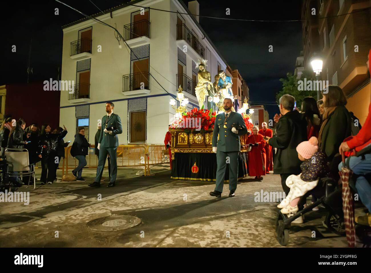 In the evening, participants in traditional attire parade down a busy ...