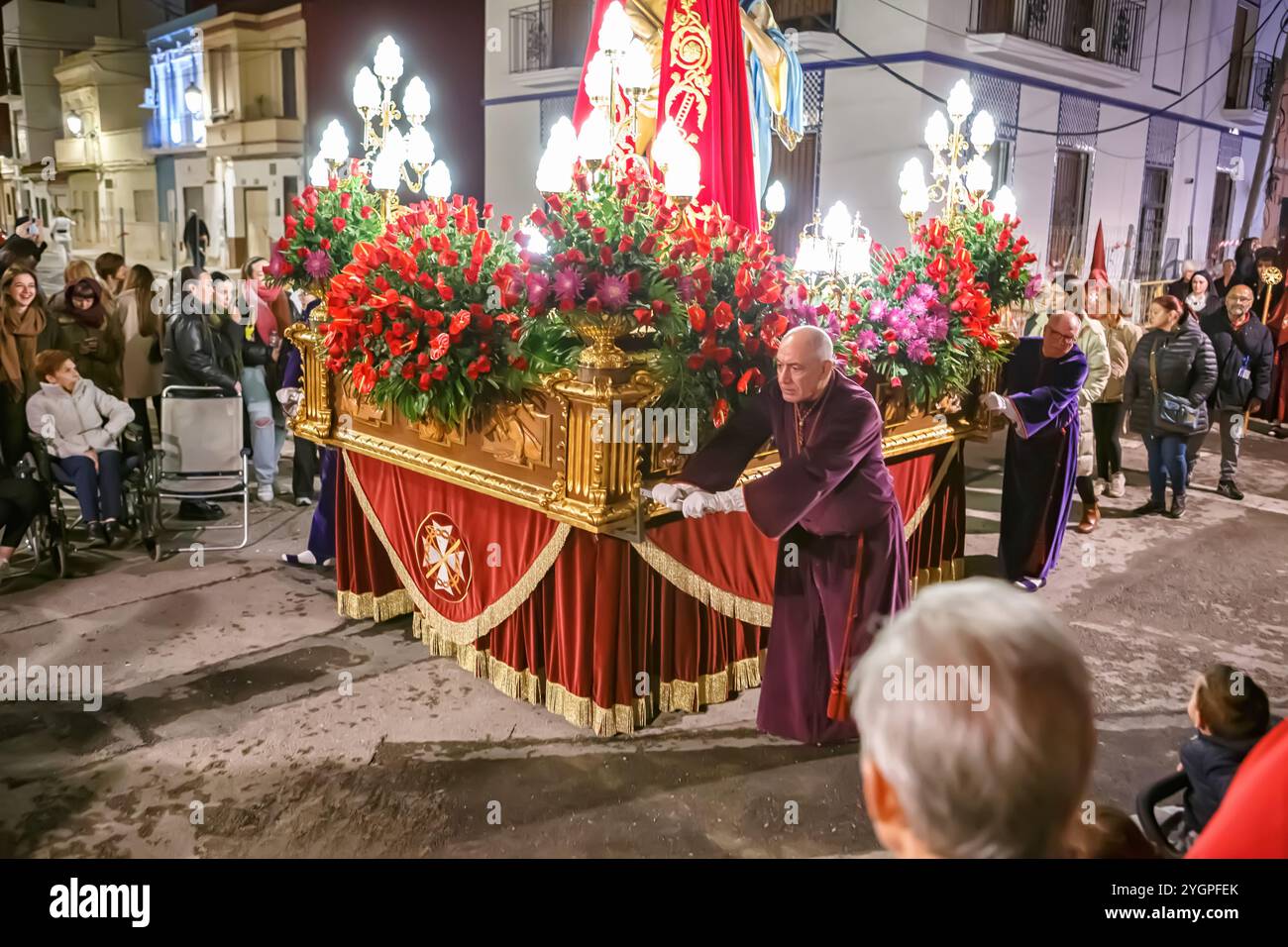In the evening, participants in traditional attire parade down a busy ...