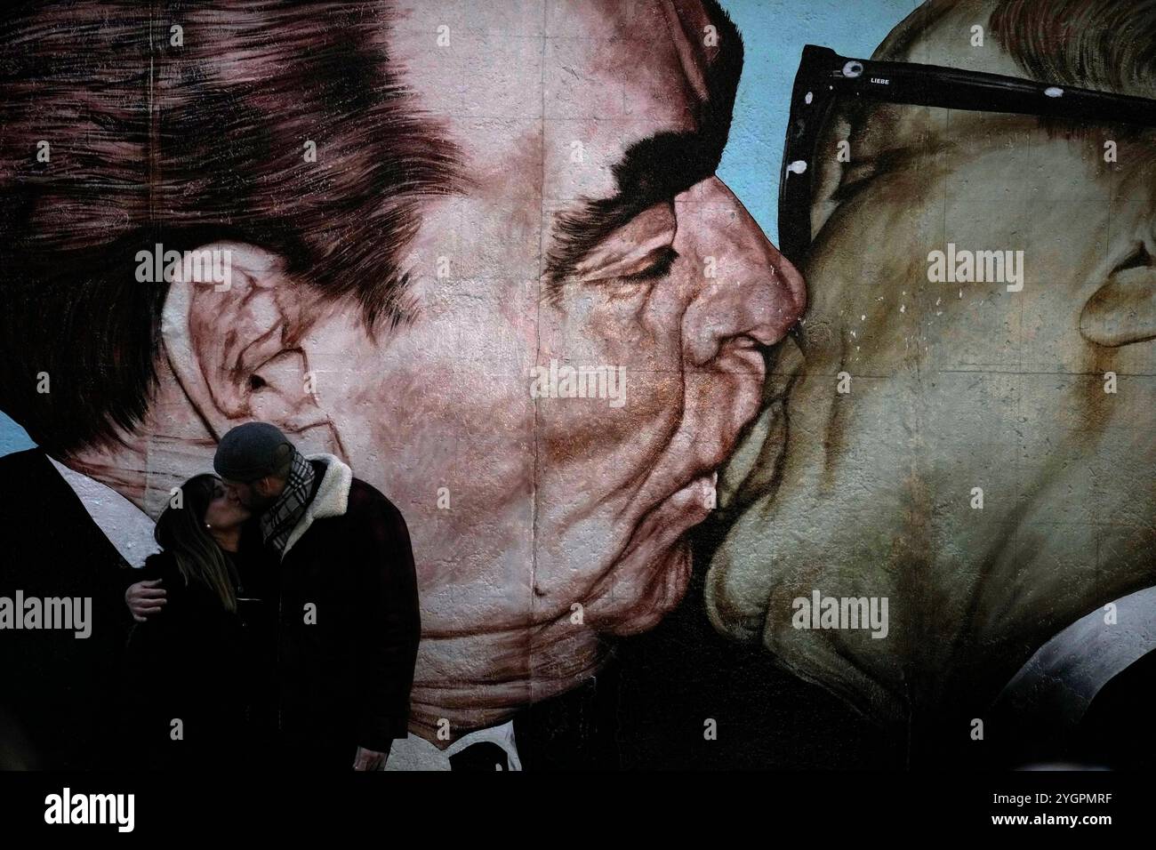 A couple exchange a kiss in front of the painting of former Soviet ...