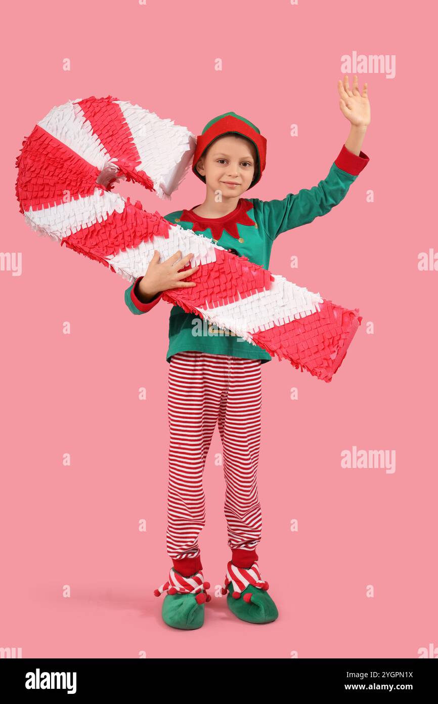 Cute little boy in elf's costume with candy cane pinata waving hand on ...