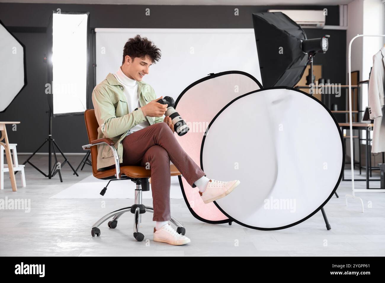 Professional happy male photographer with modern camera and softboxes ...
