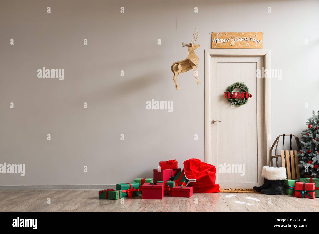 Sled, boots, gift boxes, decorated door and board with text MERRY ...