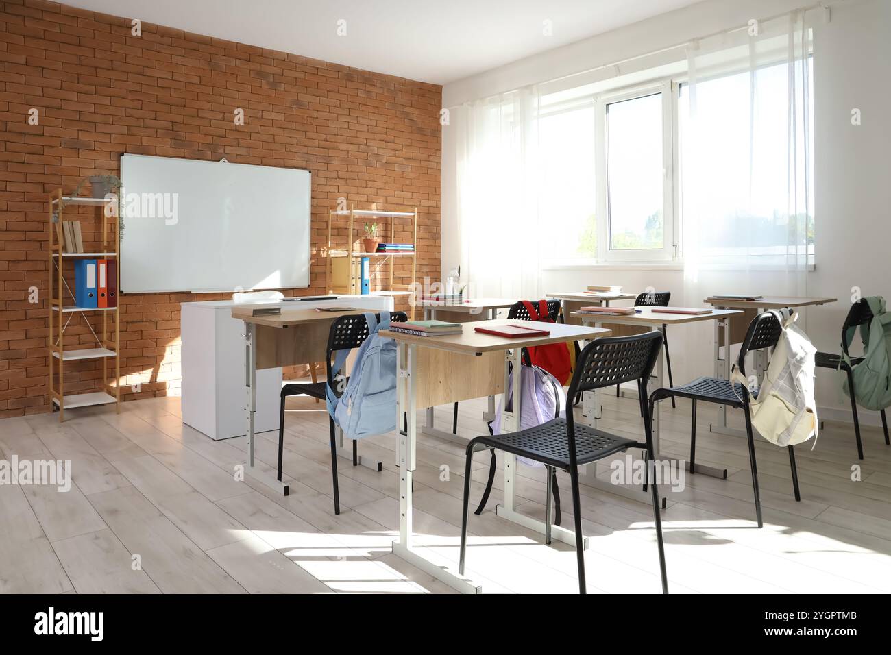 Interior of empty classroom with whiteboard, desks and shelf units ...