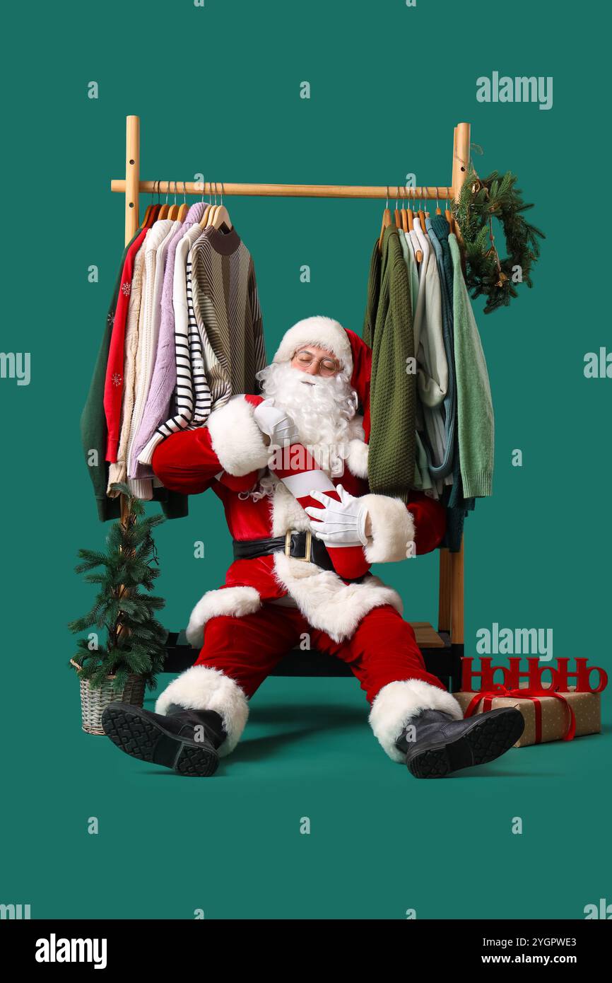 Santa Claus near rack with different clothes, wreath, gift box and ...
