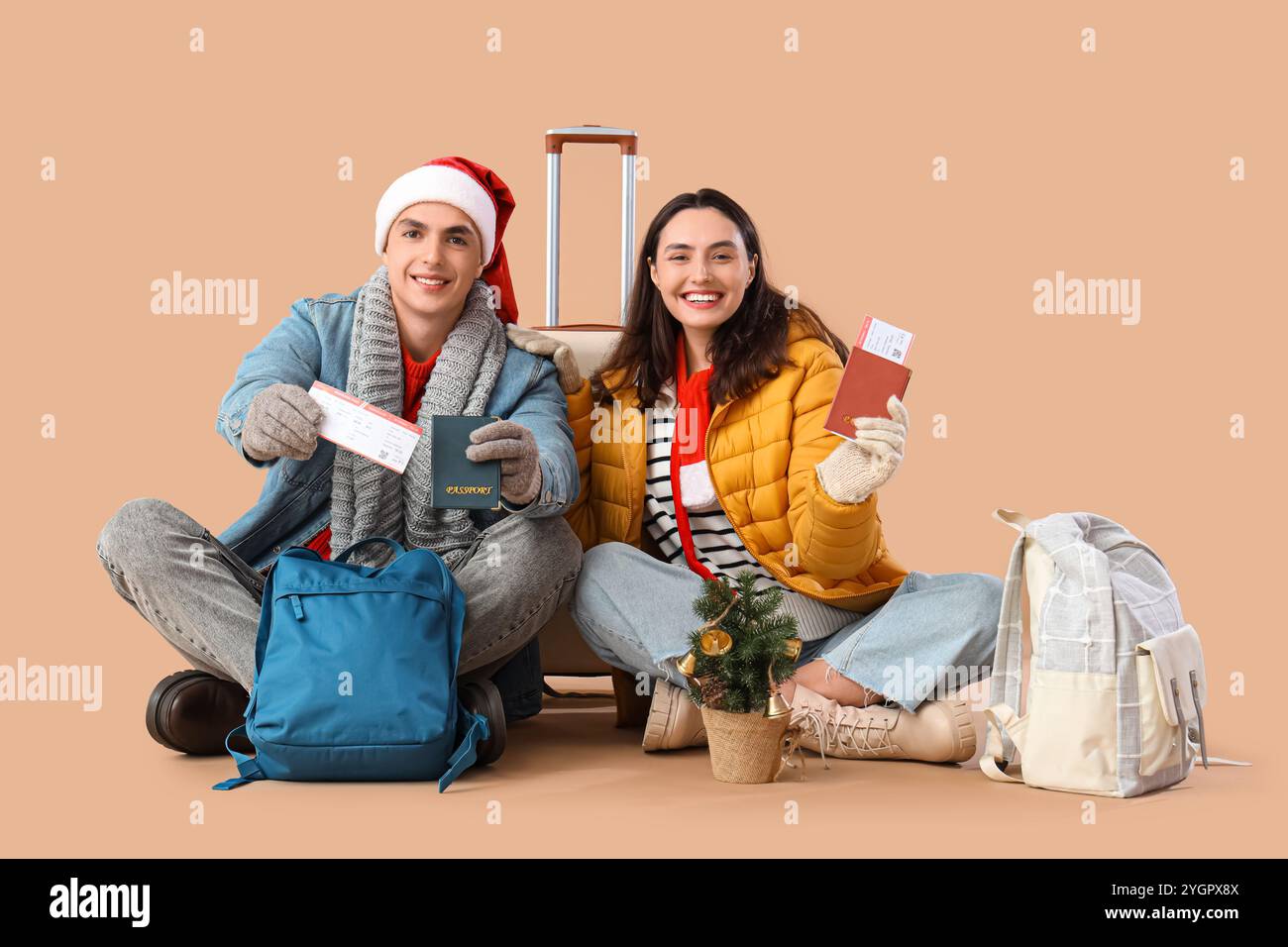 Cute young couple with passports, tickets and backpacks on beige ...