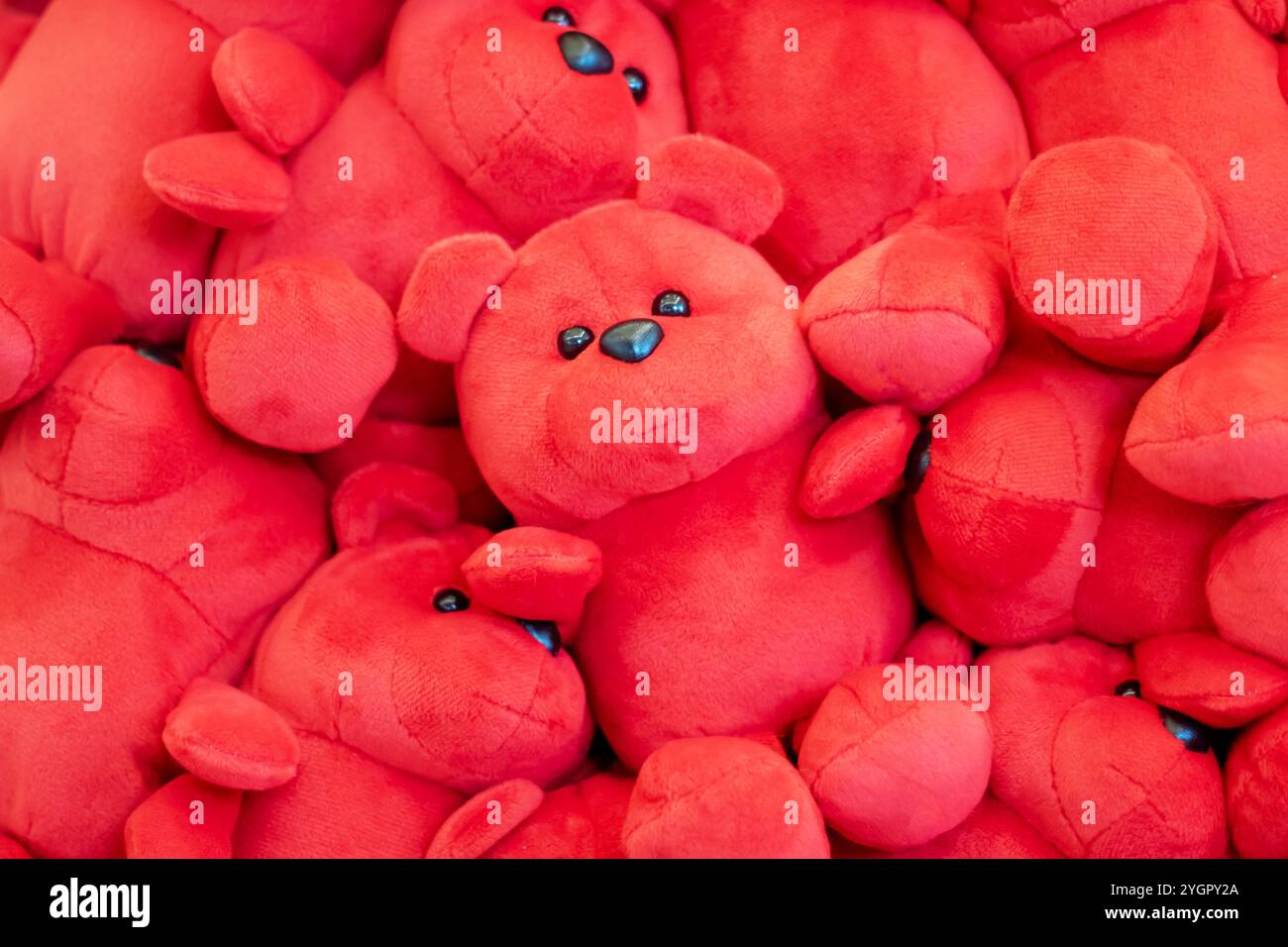There is a large pile of adorable red teddy bears that have blue eyes ...
