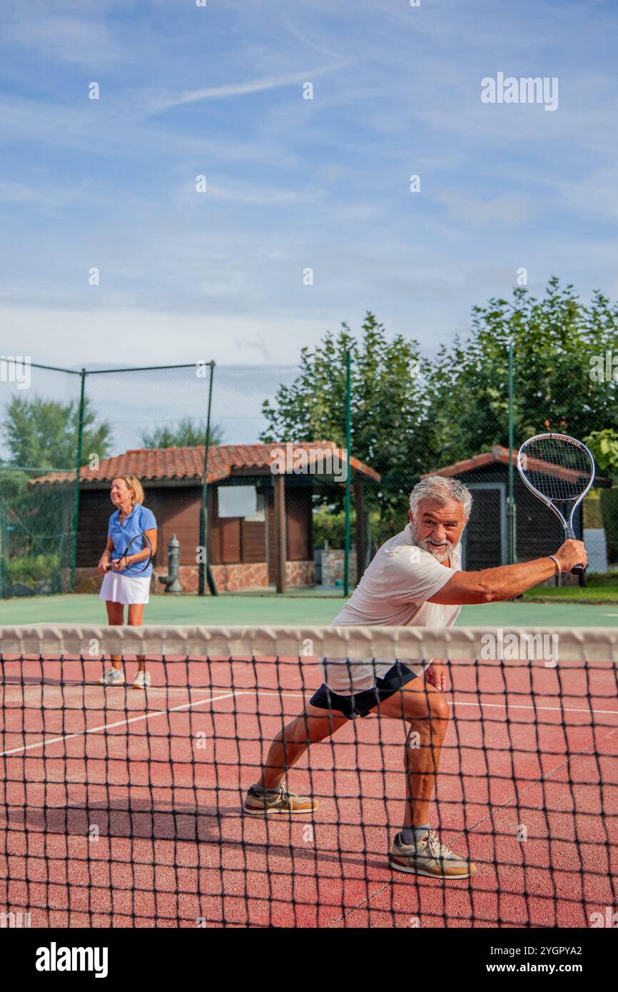 vertical senior tennis player executes a powerful backhand shot while ...