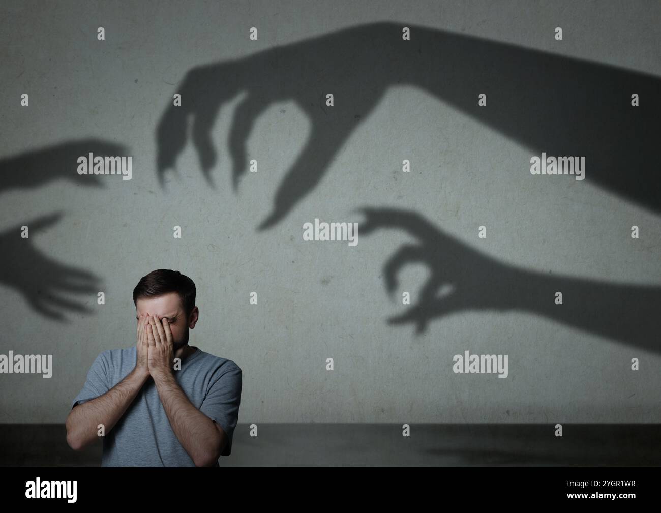 Man scared by monstrous hands reaching for him. Creepy shadows on grey ...