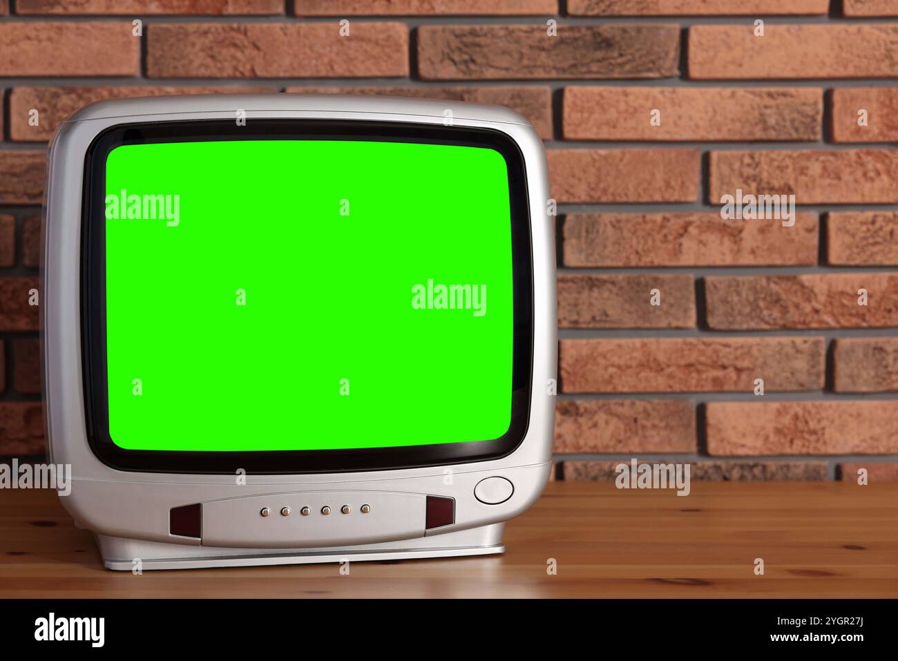 Retro Tv set with green screen on wooden table near brick wall, space ...