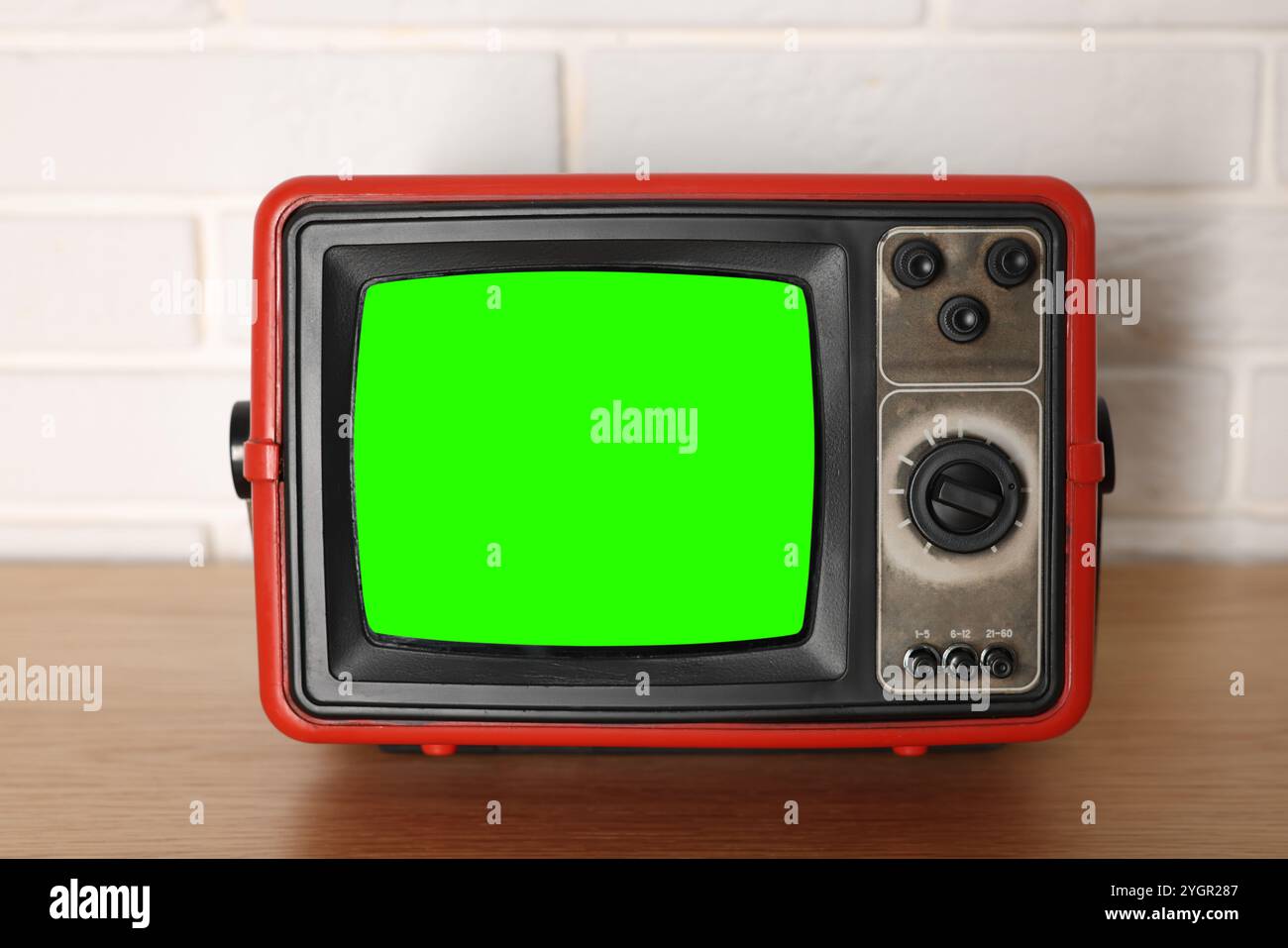 Retro Tv set with green screen on wooden table near white brick wall ...