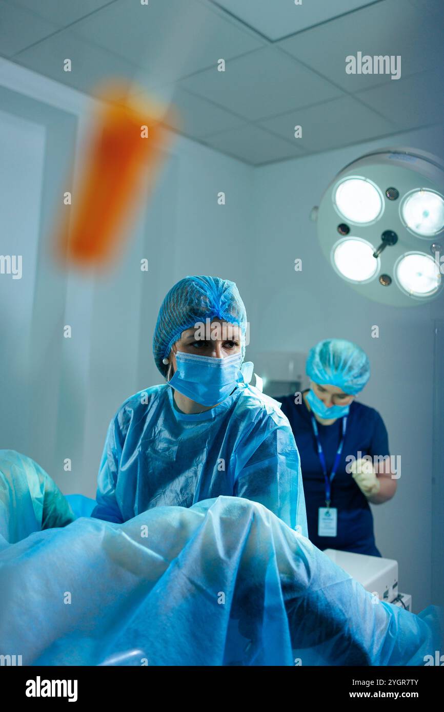 A female doctor performs an operation in a sterile operating room ...