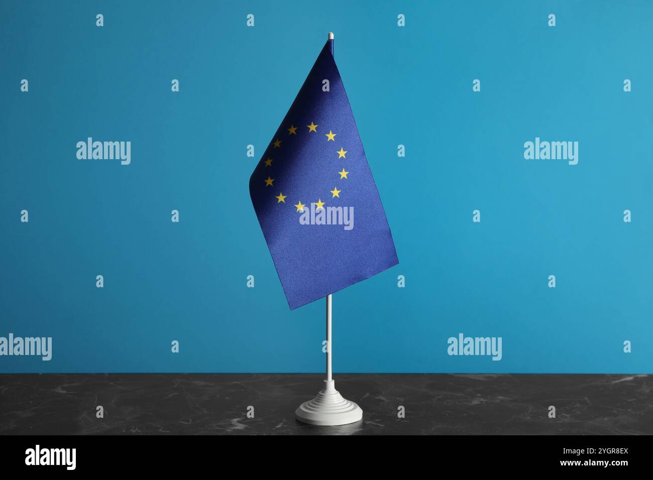 One flag of European Union on grey marble table against light blue ...