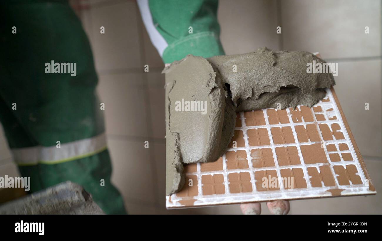 The master puts tiles on the wall. Master in overalls puts ceramic ...