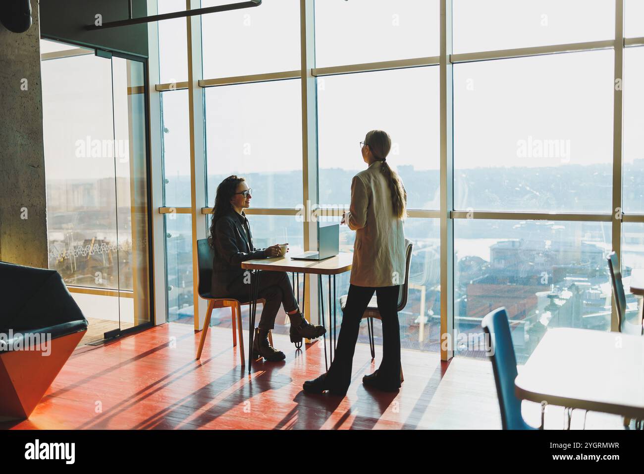 Two female co-workers and colleagues discussing working together on ...