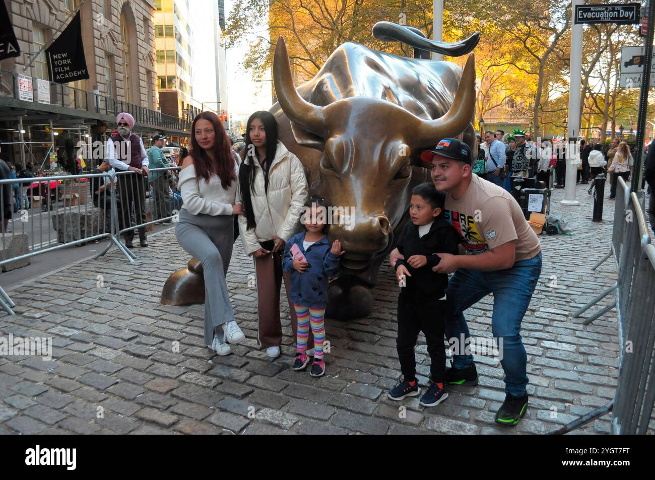 People take photos by the "Charging Bull" statue in the Financial ...