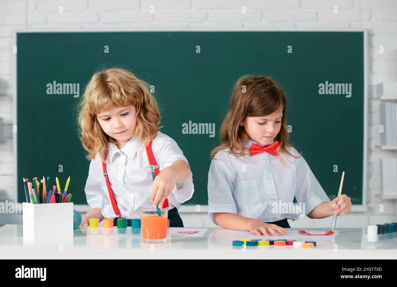 School children drawing a colorful pictures with pencil crayons in ...