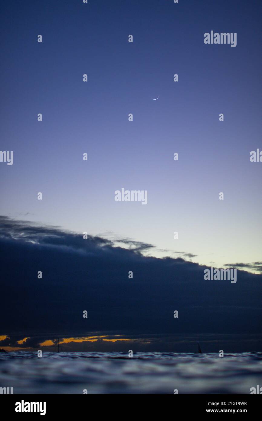A delicate crescent moon rises over the darkening ocean, Waikiki Stock ...