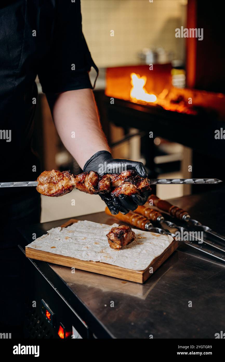 Chef holding skewered grilled meat ready to serve, highlighting BBQ ...