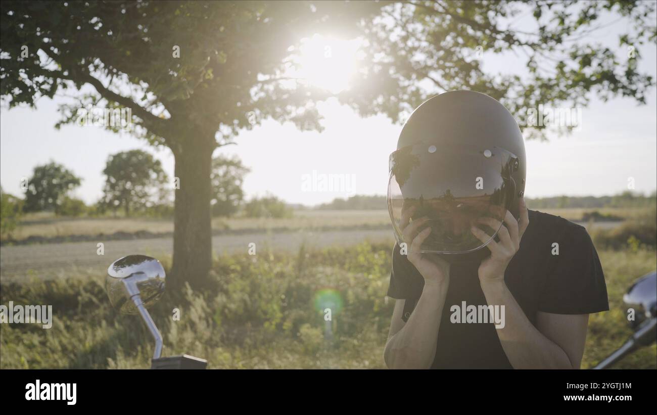 Motorcyclist takes off his helmet. rider on a motorcycle taking off his ...