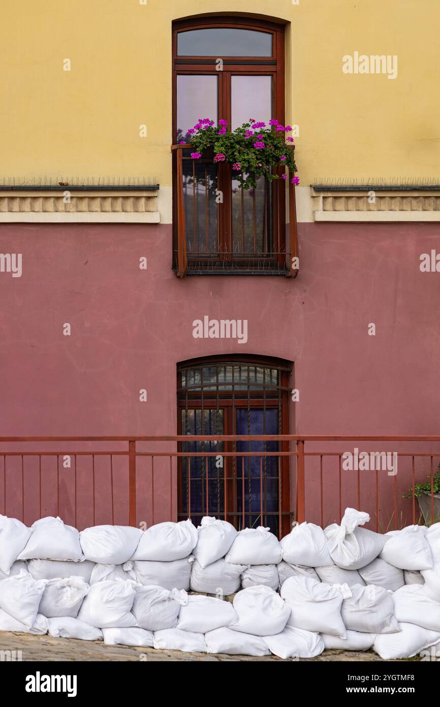 Protective sandbag barrier stacked in front of urban building with pink ...