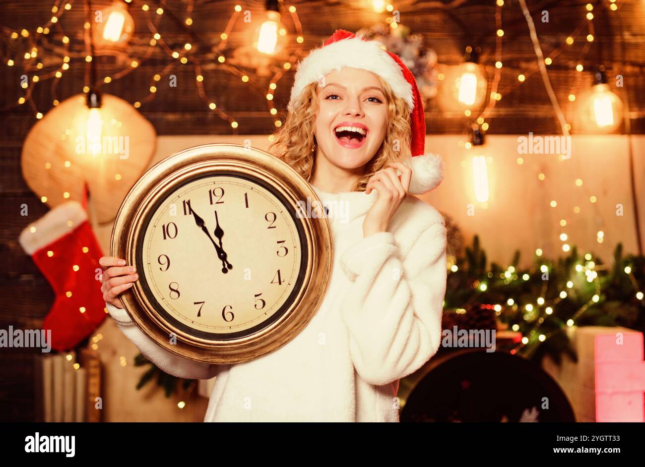 Make wish. Happy emotional girl Santa hat hold vintage clock. Time to ...