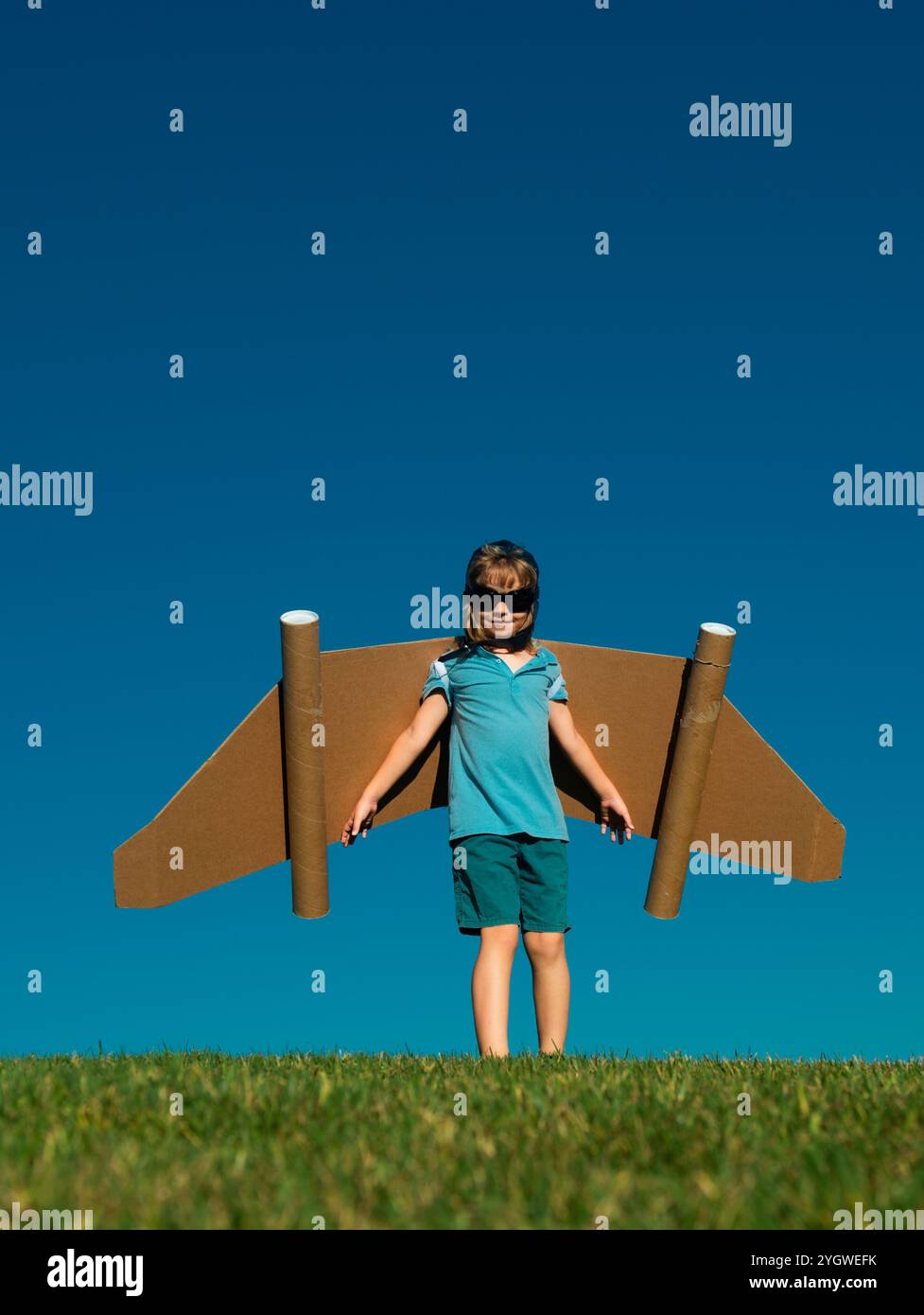 Child boy with paper wings against blue sky. Kid with toy jetpack ...