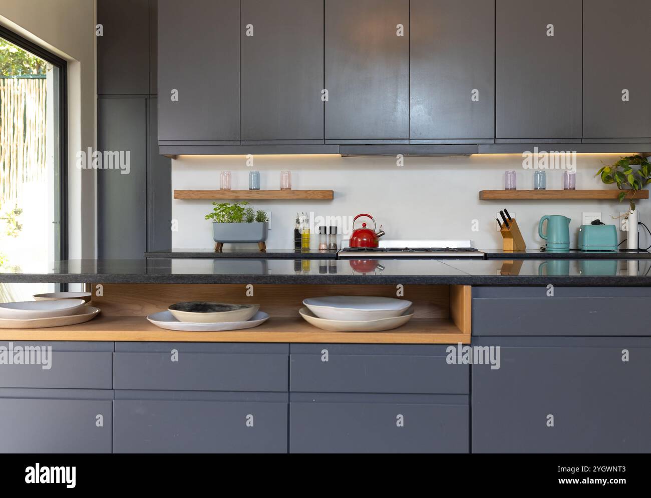 Modern kitchen with sleek cabinets and red kettle on stove, bright and ...