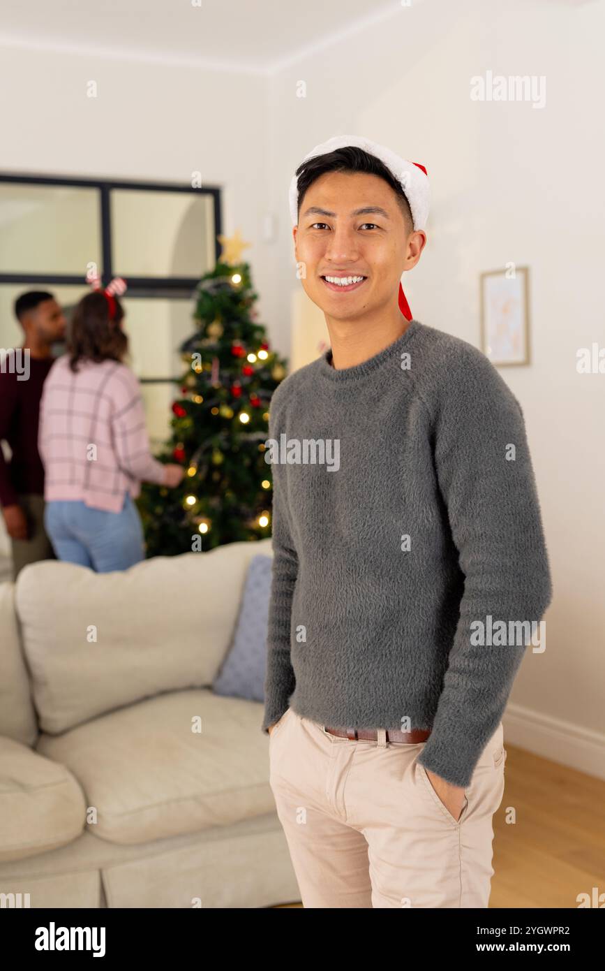 Asian man smiling at home during Christmas celebration with multiracial ...