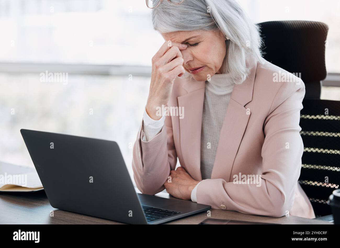 Mature woman, headache and strain with laptop for stress, bankruptcy or ...