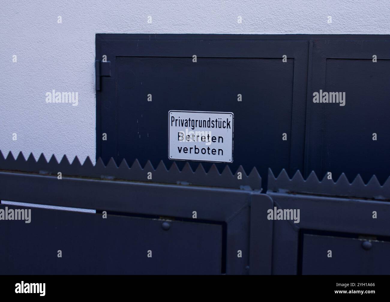 Behind a dark metal fence with a tooth border there is a sign lettering ...