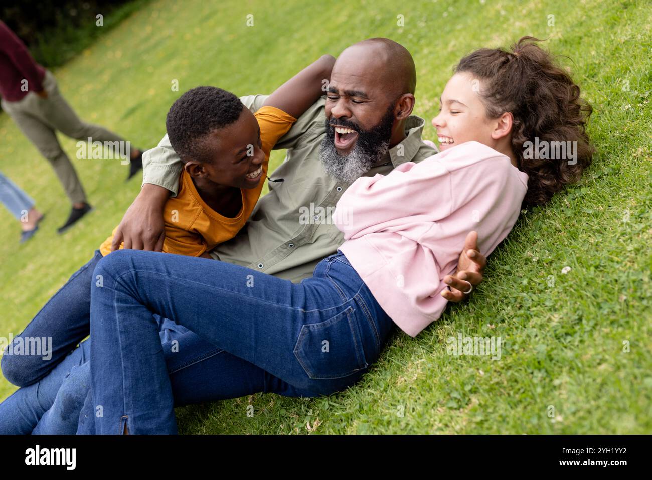 multiracial family laughing together while lying on grass in park ...