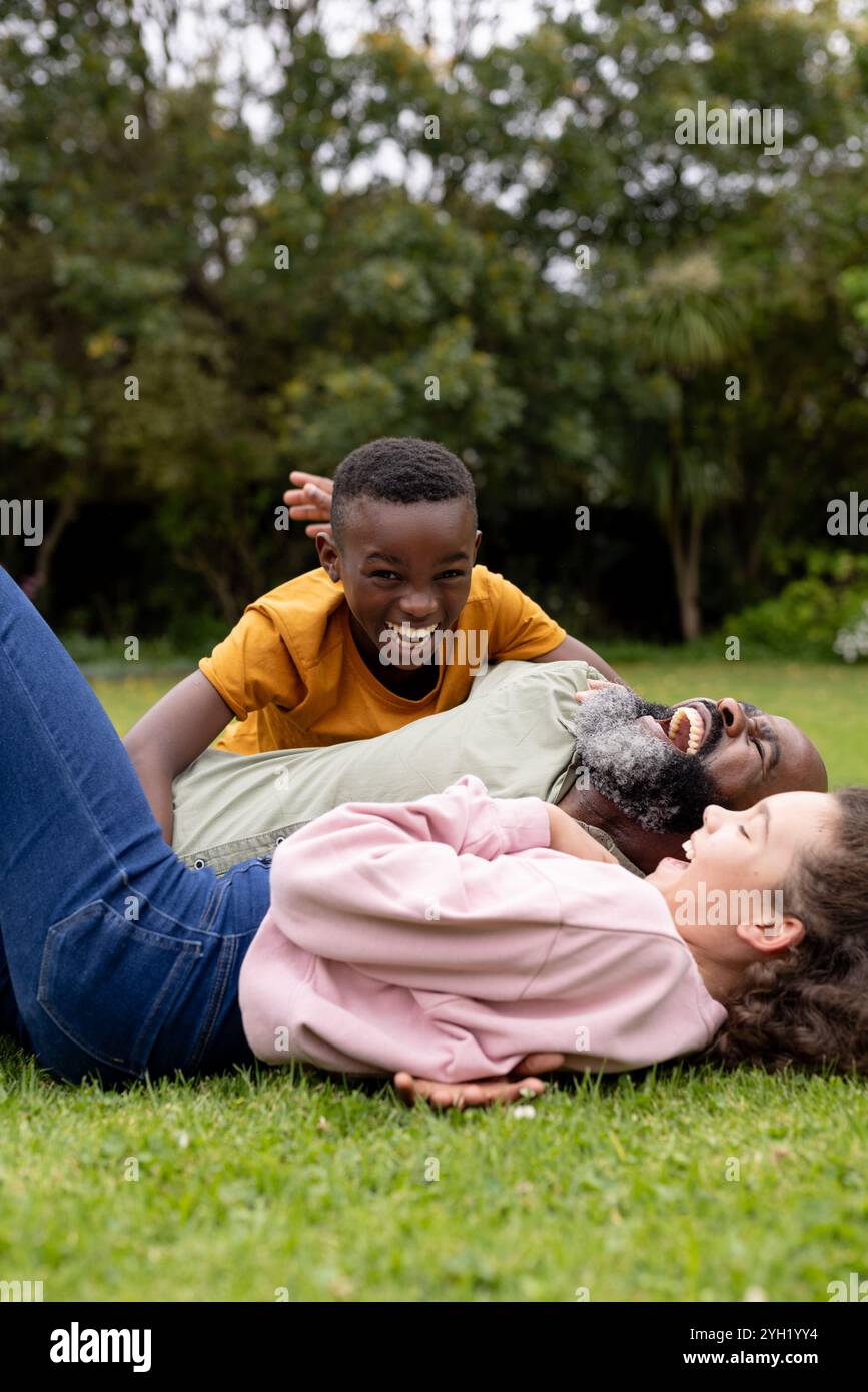 multiracial family enjoying playful moments together on grass, laughing ...