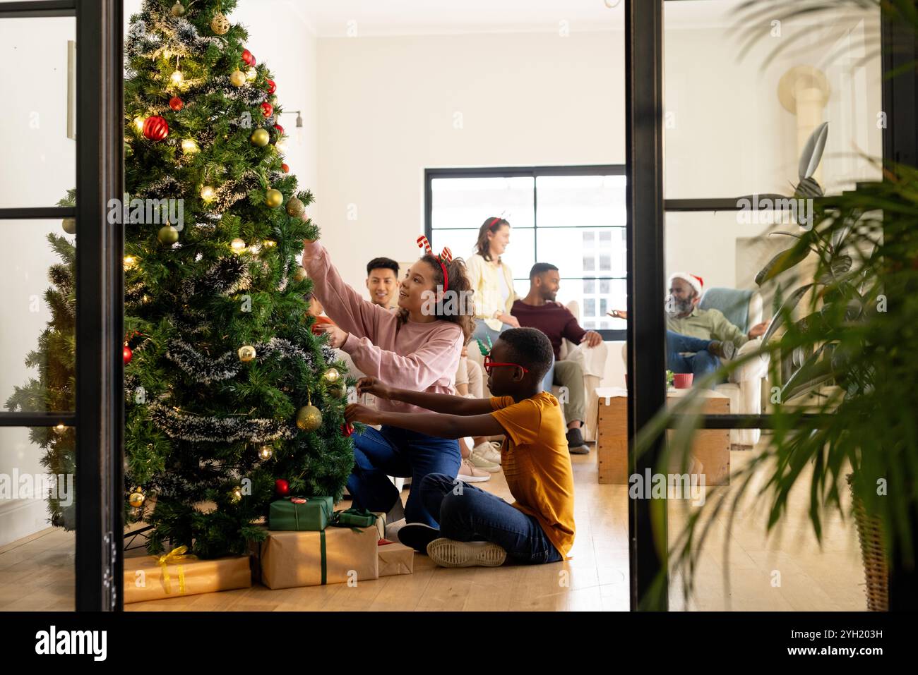 Multiracial family decorating christmas tree together at home, at home ...