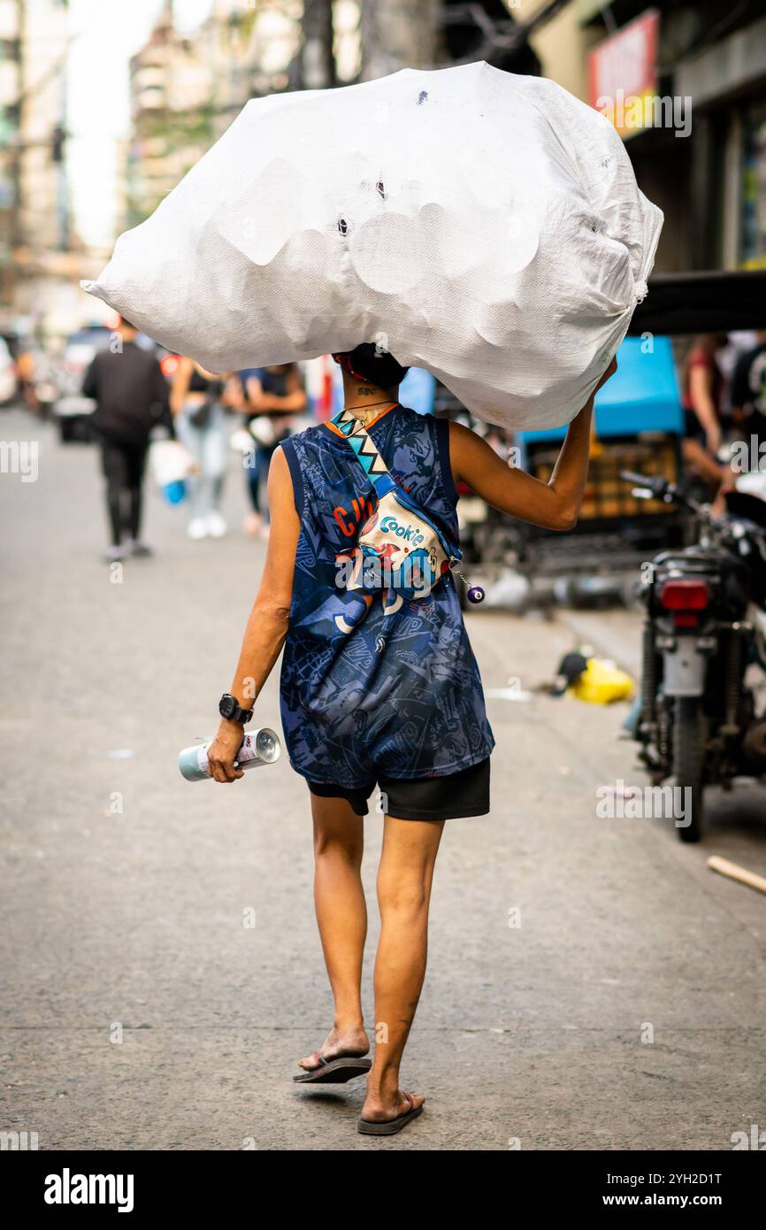 A Filipino market worker carries his goods along the street in a market ...