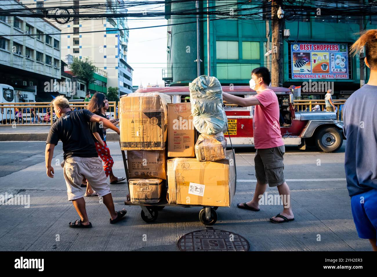A Filipino market worker pulls his trolley along the street in a market ...