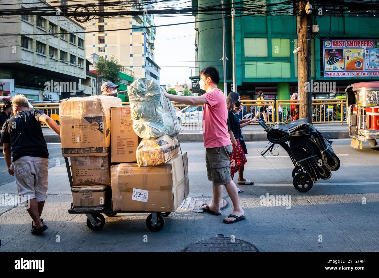 A Filipino market worker pulls his trolley along the street in a market ...