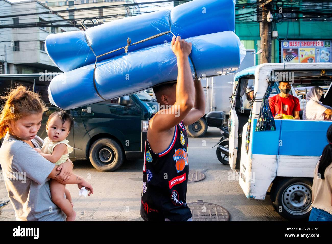 A Filipino market worker carries his goods along the street in a market ...