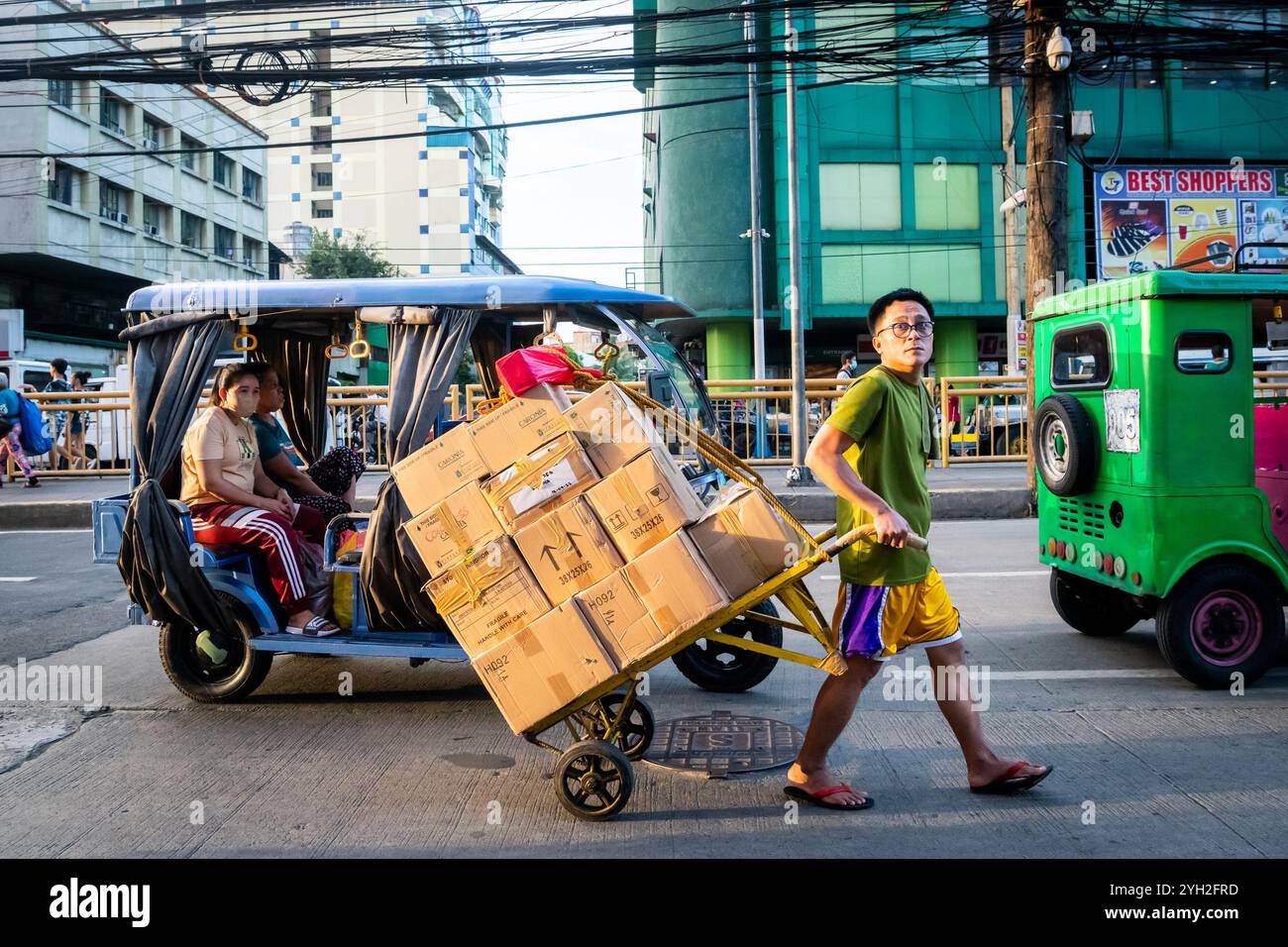 A Filipino market worker pulls his trolley along the street in a market ...
