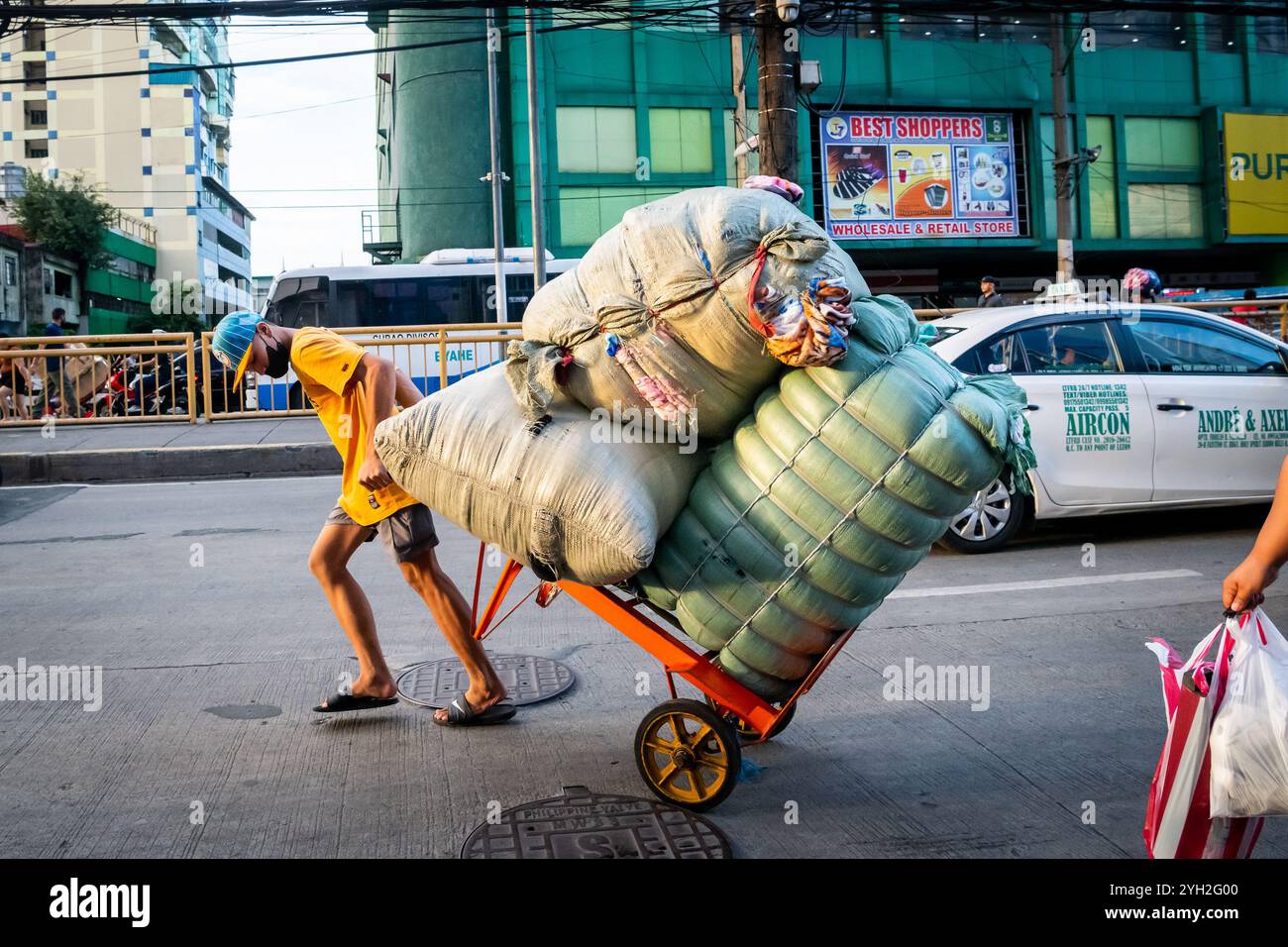 A Filipino market worker pulls his trolley along the street in a market ...