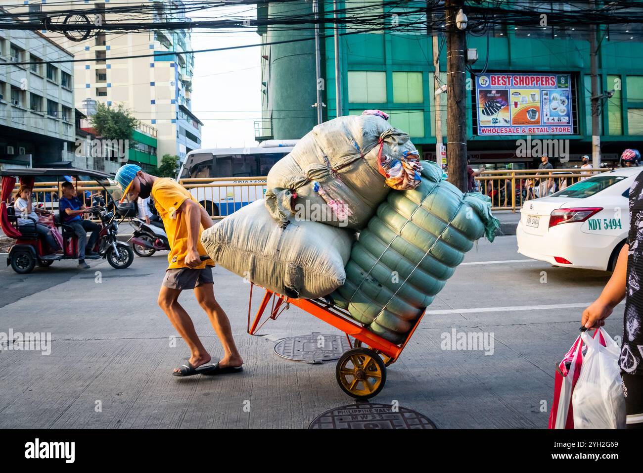 A Filipino market worker pulls his trolley along the street in a market ...