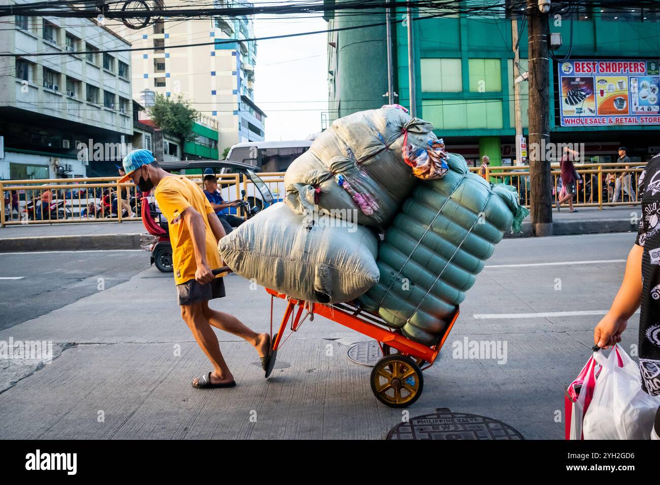 A Filipino market worker pulls his trolley along the street in a market ...