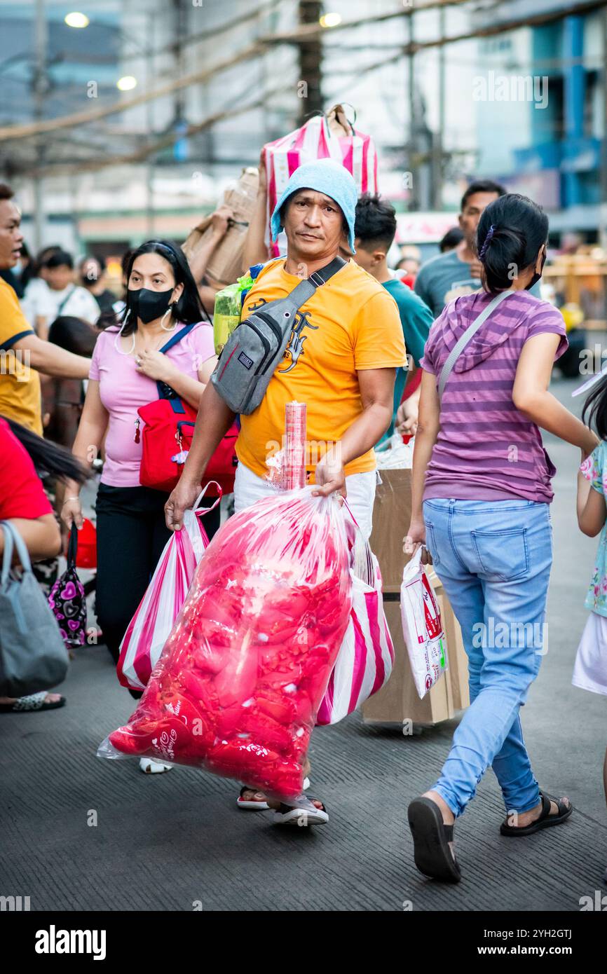 A Filipino market worker carries his goods in the street in a market in ...