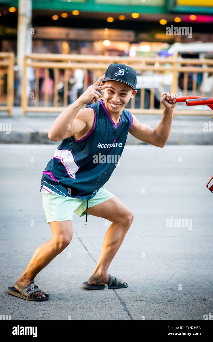 A Filipino market worker pushes his trolley along the street in a ...