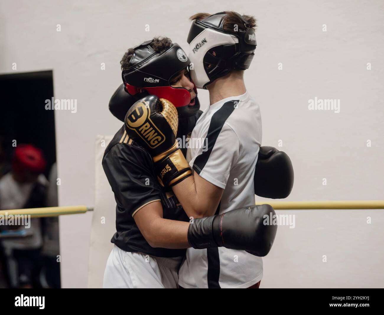 Two men in boxing gloves hug each other. One of the men is wearing a ...